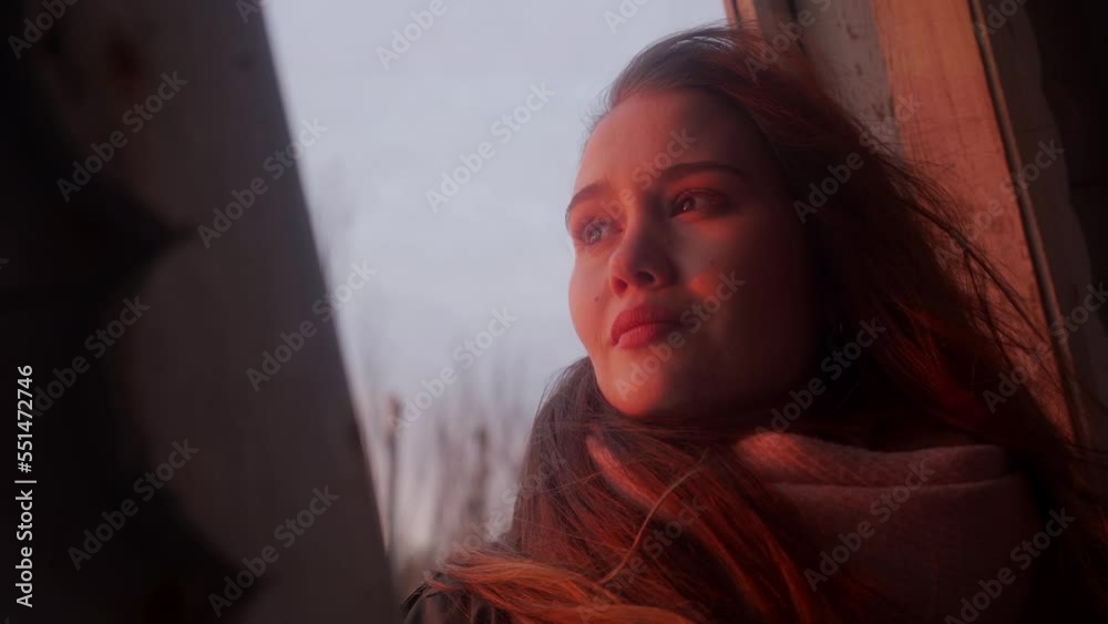Enigmatic woman sits on windowsill of abandoned wooden leaning house on ...