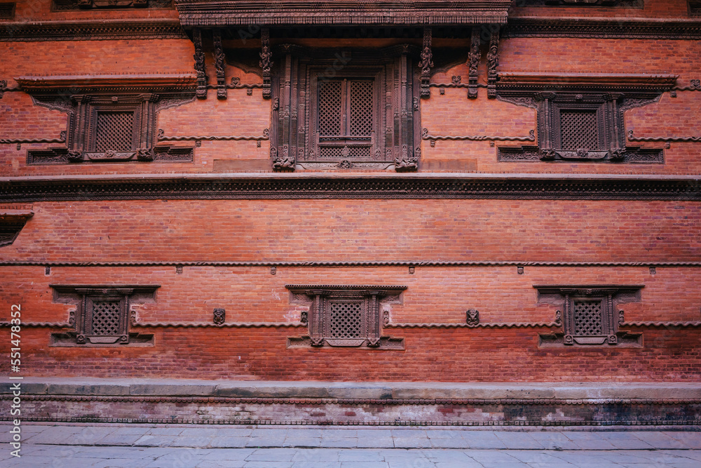 Frontal view of a red brick temple wall and ancient wood carvings in ...