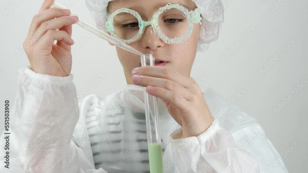 A kid in a doctor's suit and glasses. A boy in the laboratory conducts ...