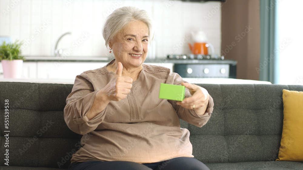 The old woman is holding something green in her armchair, showing a ...