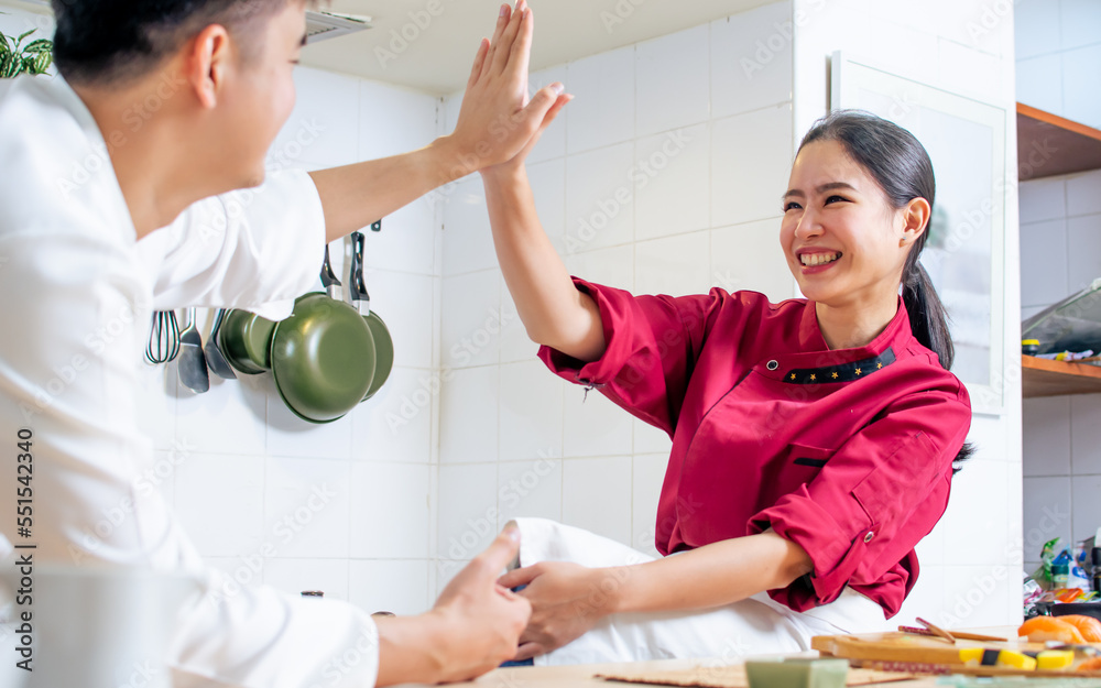 Two young Asian professional couple chefs wearing uniform, hat, happily ...