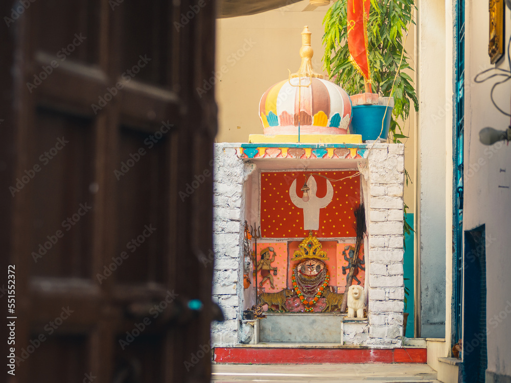 An open door with a small sunlit Hindu temple to venerate the goddess ...