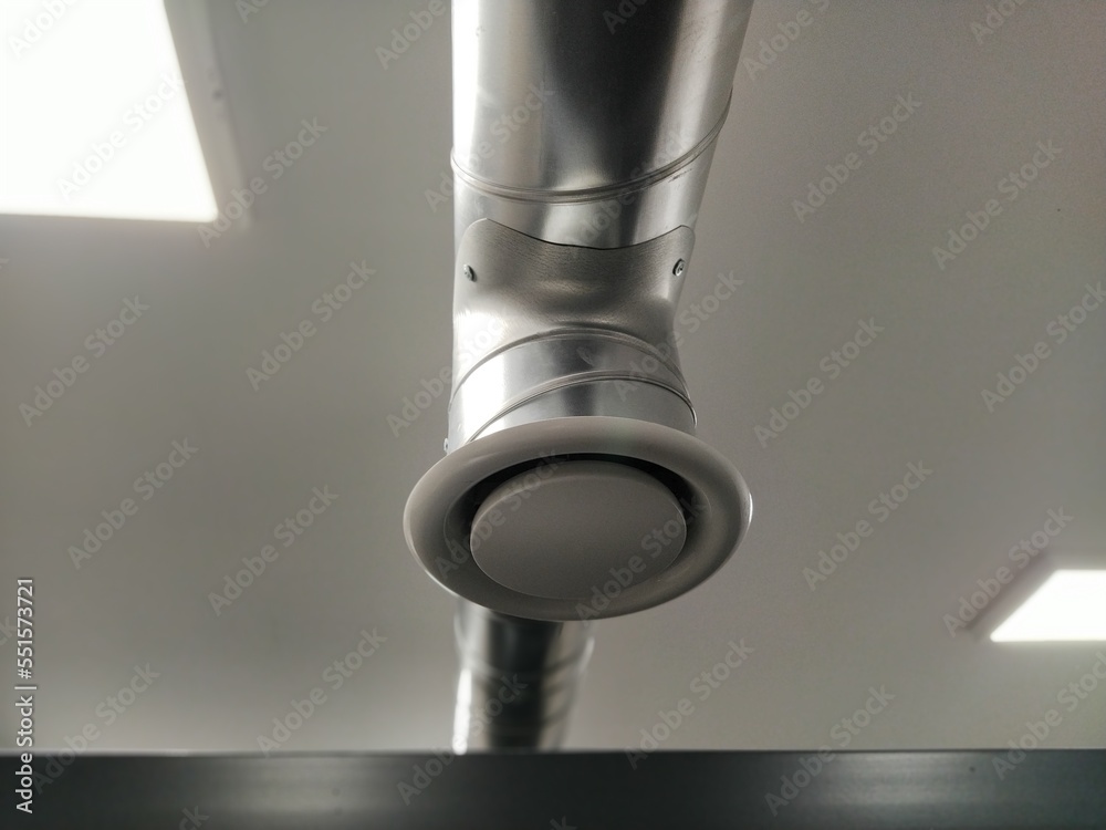 Extractor hood in a public toilet. Round metal pipe with gray air ...