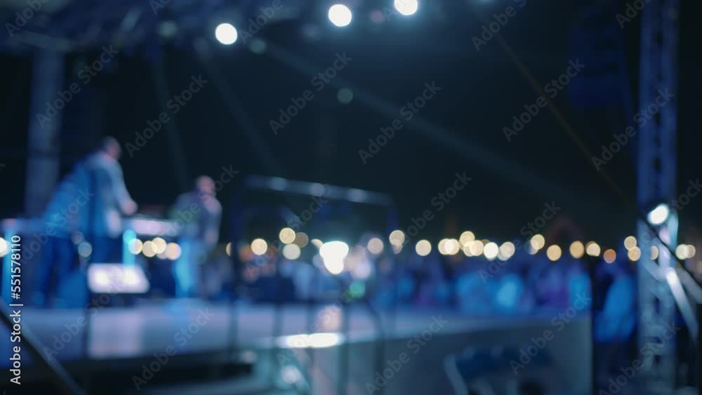 Blurred view of concert with a DJ on stage and crowd of people with ...