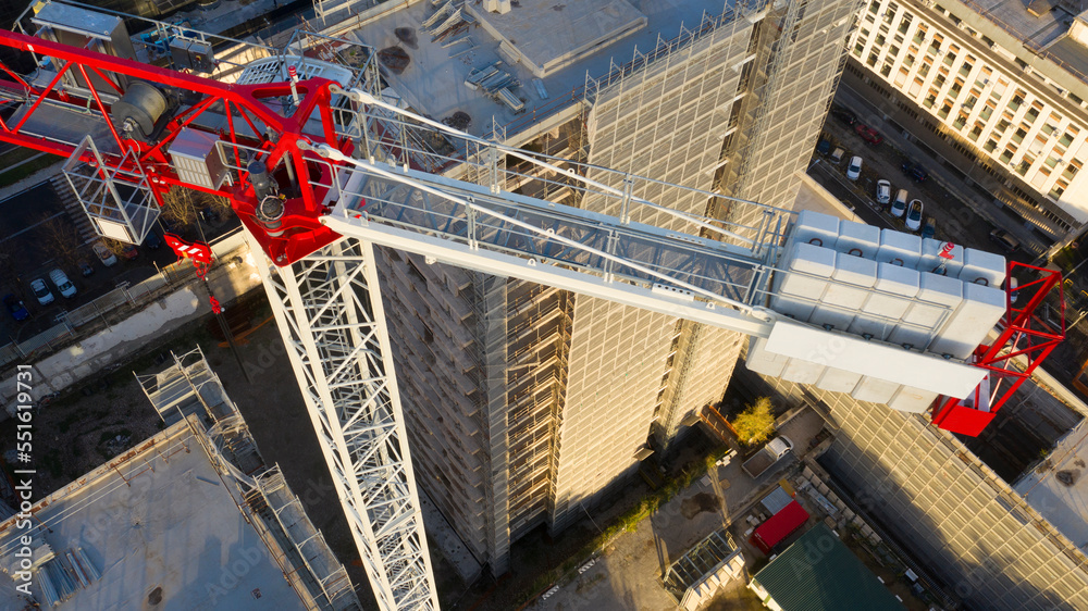 Aerial view of a red and white industrial tower crane operating in high ...
