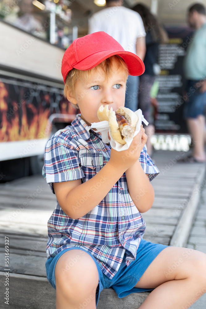 Cute adorable pensive little boy kid enjoy eating hot dog sausage in ...