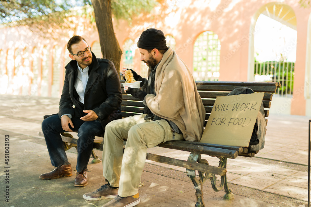 Caucasian man sitting with a poor homeless man on the bench Stock Photo ...