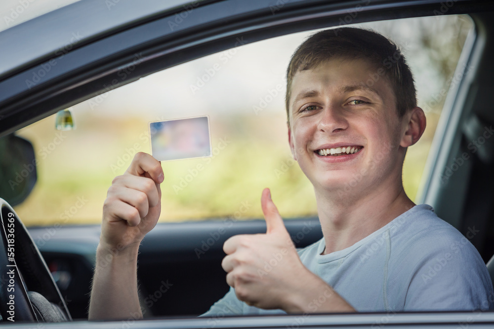 Foto de Happy and proud guy showing his driver license out of the car ...