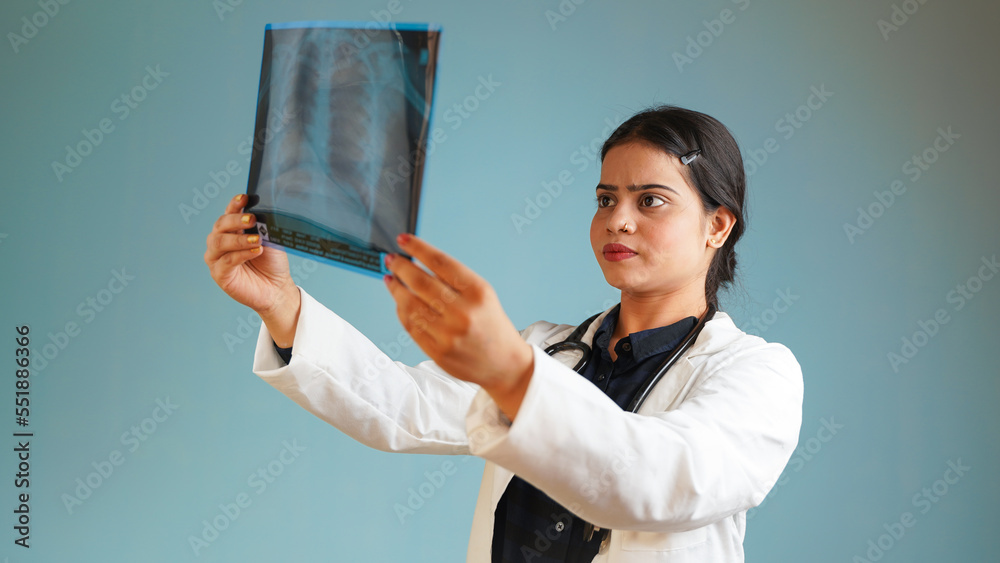 Portrait of a young female doctor examining patient's x-rays scan ...