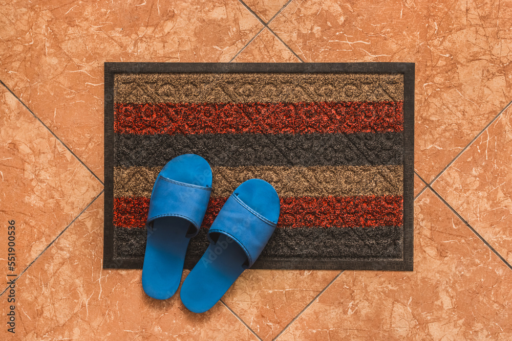 Blue homemade slippers stand on the foot carpet against the background ...