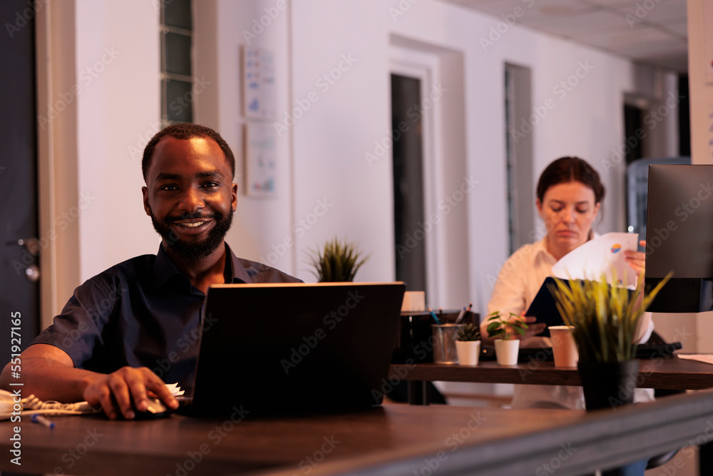 Smiling employee working on laptop in coworking space portrait ...