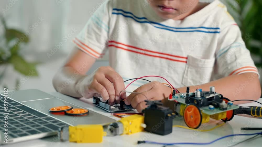 Asian kid boy plugging energy and signal cable to sensor chip with ...