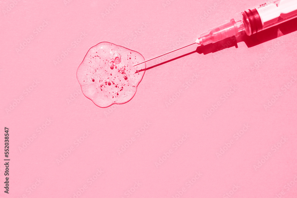 Sterile medical syringe and drop of gelatinous liquid on pink ...