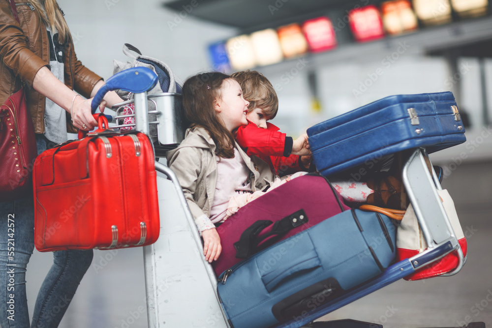 Two little kids, boy and girl, siblings and mother at the airport ...
