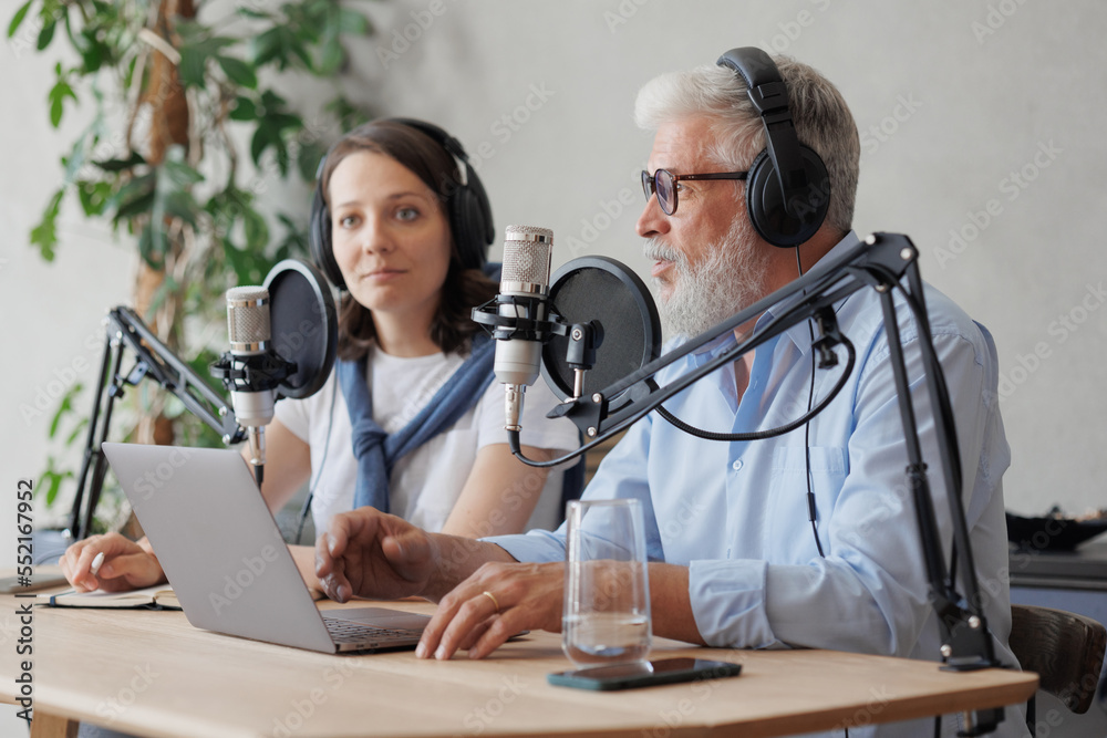 older man and female presenter in a recording studio create a podcast ...