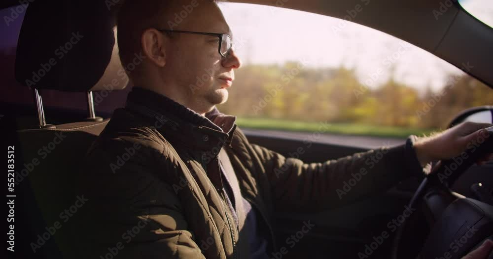 Profile of man in driving car through countryside. Young guy riding on ...