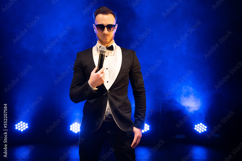 handsome presenter and showman in a stylish suit with a microphone on ...