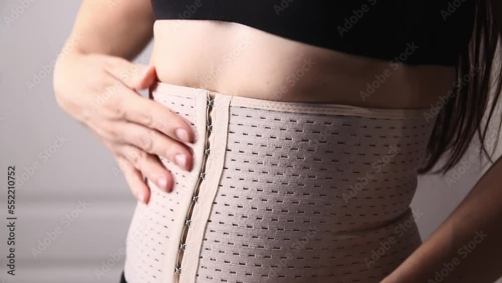 Closeup woman getting dressed, hooking on corset hooks using hands ...