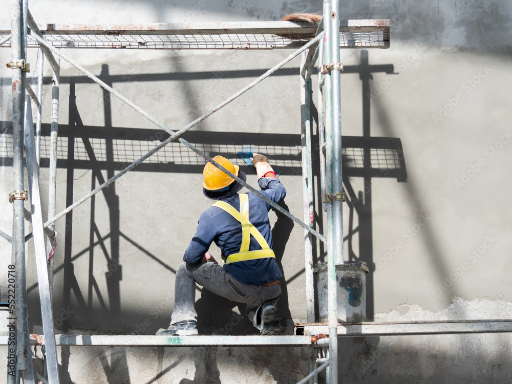 Construction worker plastering concrete wall at a construction site ...