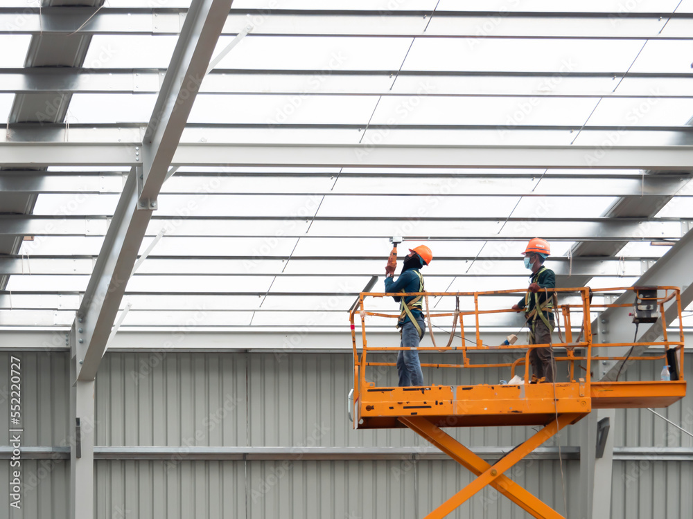 Foto de Workers install lighting fixture in a hug industrial warehouse ...