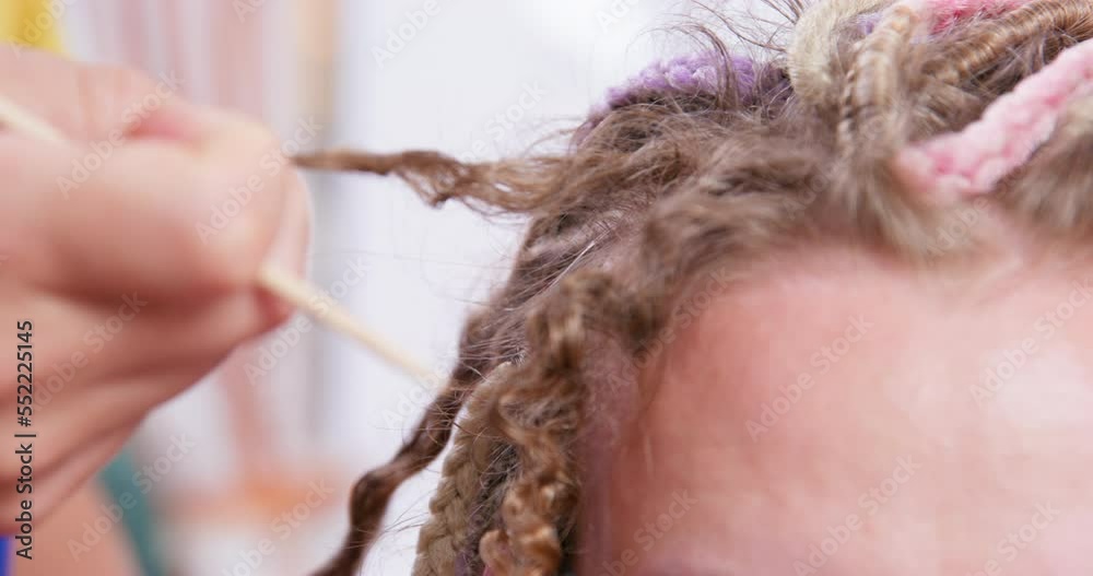 Hairdresser hand unravels the Afro braids carefully pulls out the hair ...