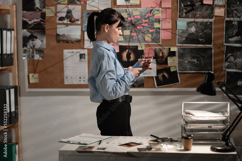Serious female detective working in her office with evidence Stock ...