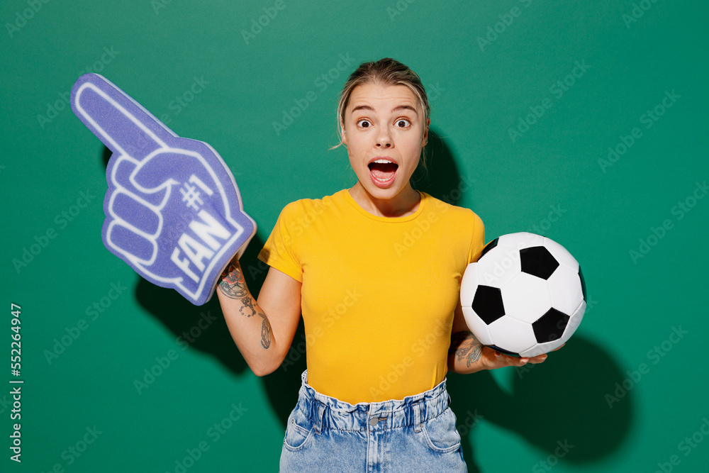 Young shocked woman fan in basic yellow t-shirt foam 1 glove finger up ...