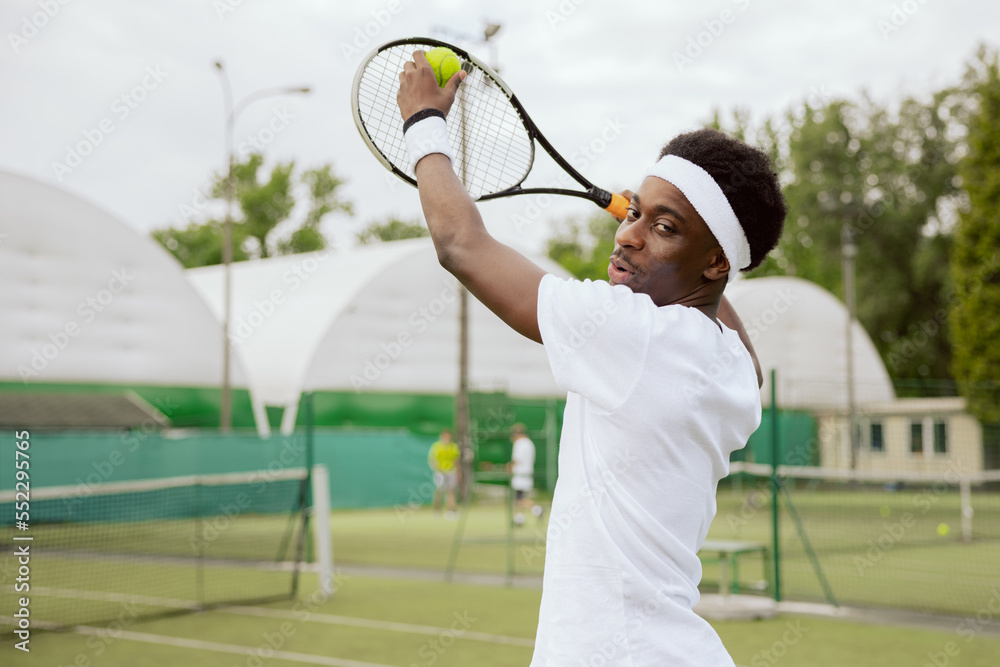 Famous tennis player of African appearance trains on tennis court and ...