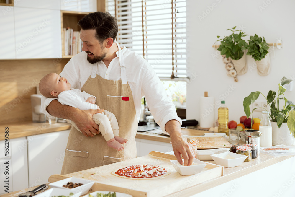 Foto de Adorable lovely baby in father's hands resting cooking with dad ...