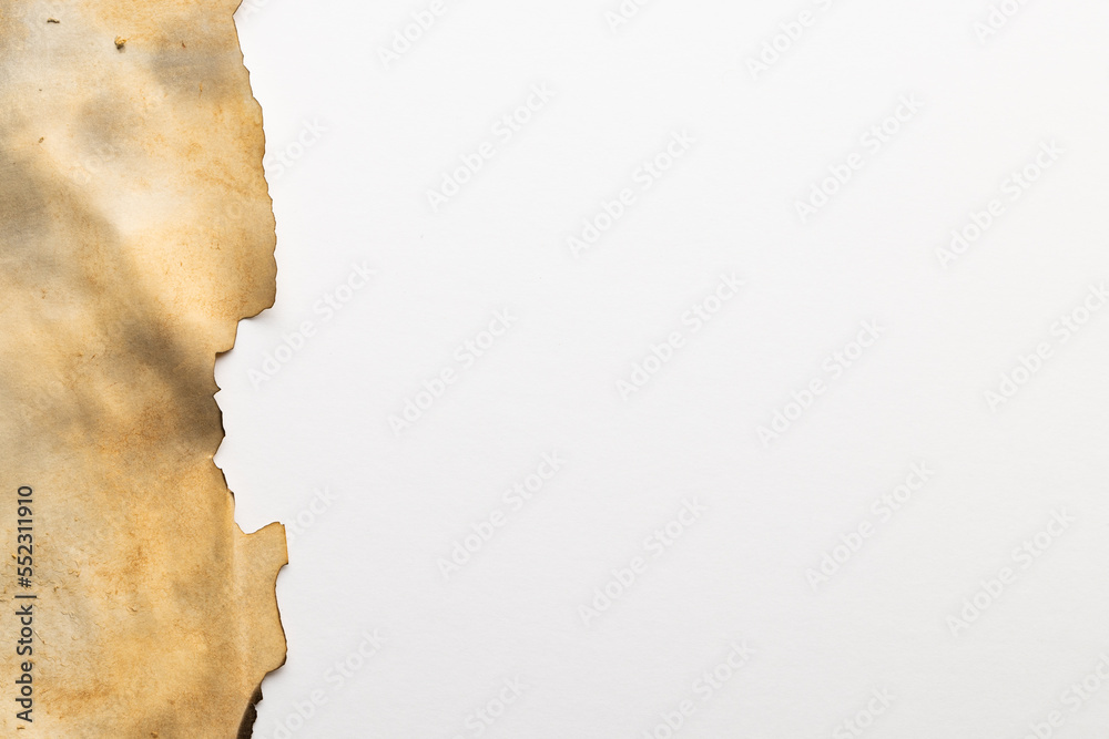 Burned and stained piece of paper with copy space on white background ...