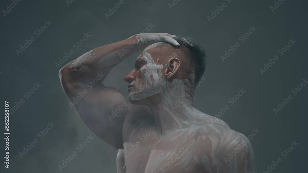 Bodybuilder with naked torso runs his hand through his hair with white ...