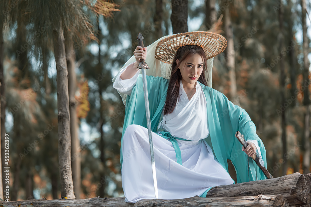 Portrait woman in a Chinese costume with a sword in the forest. Chinese ...