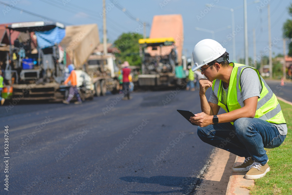 Male civil engineer working at paved road construction site Control and ...