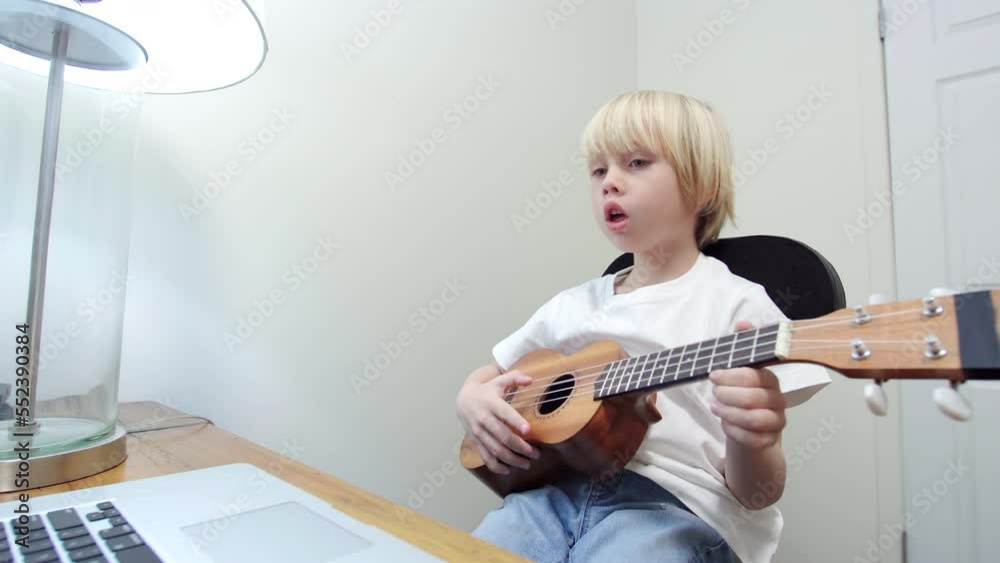 Zooming out view of a 5 years old caucasian boy is having an online ...