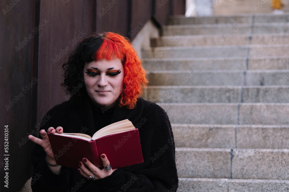 Transgender girl reading a book on the stairs. Stock Photo | Adobe Stock