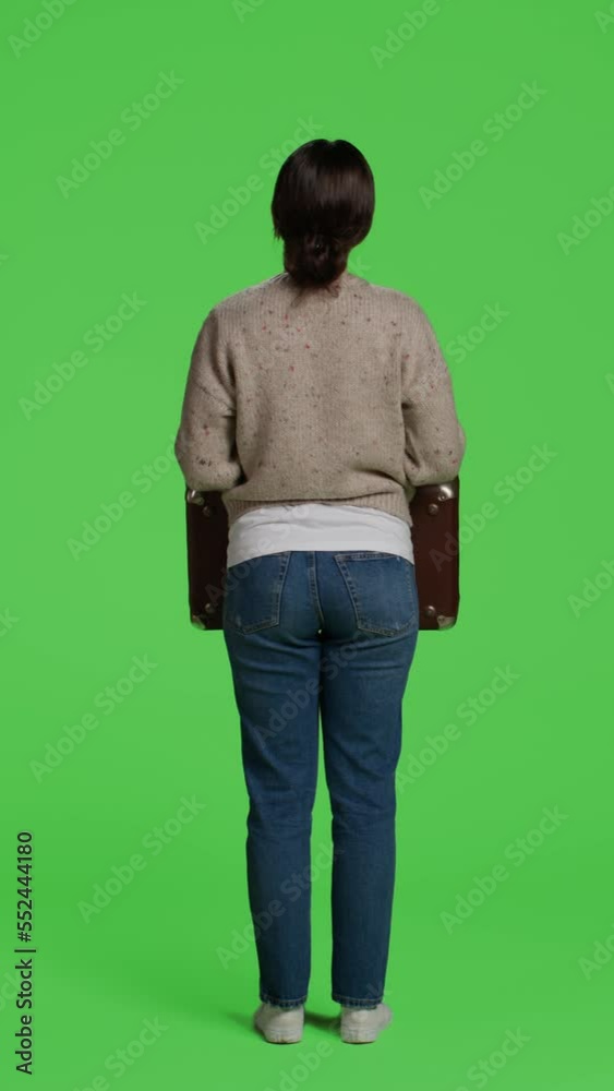 Vertical video: Back view of casual person carrying suitcase in studio ...