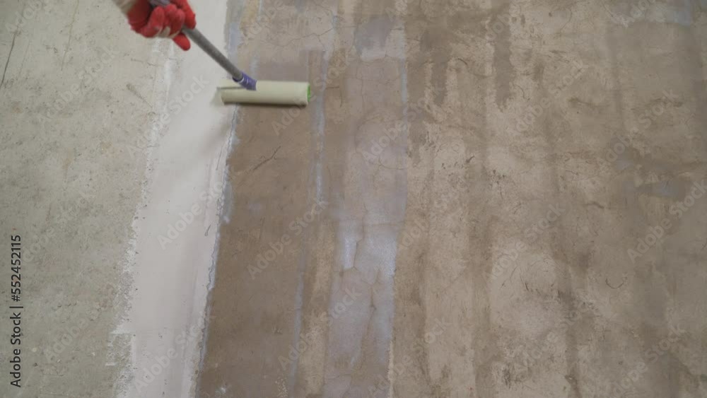 Male hand applies fresh paint and primer to the surface of the wall ...