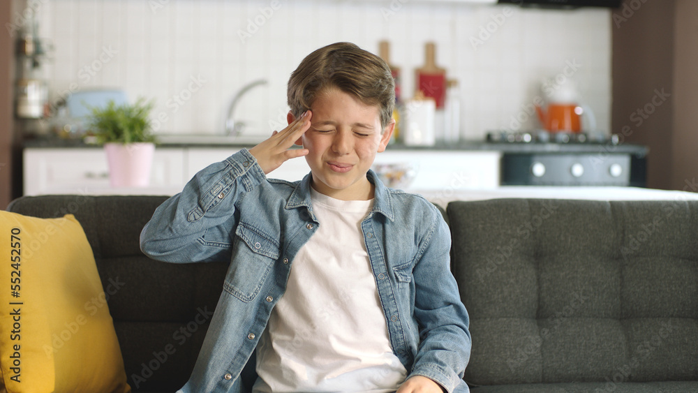 A little boy has a headache, holding his head with his hands.Little boy ...