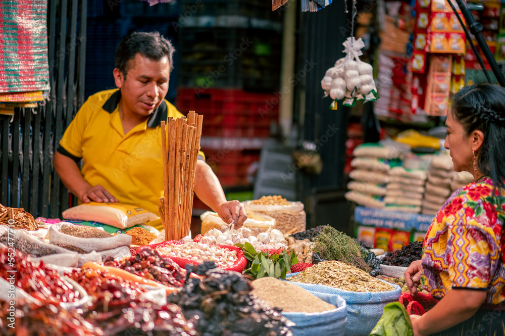 Retrato de un vendedor en su tienda atendiendo a una mujer que le compra. Stock-foto | Adobe Stock