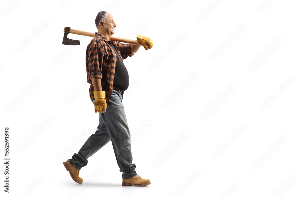 Full length profile shot of a mature man walking and carrying an axe on ...