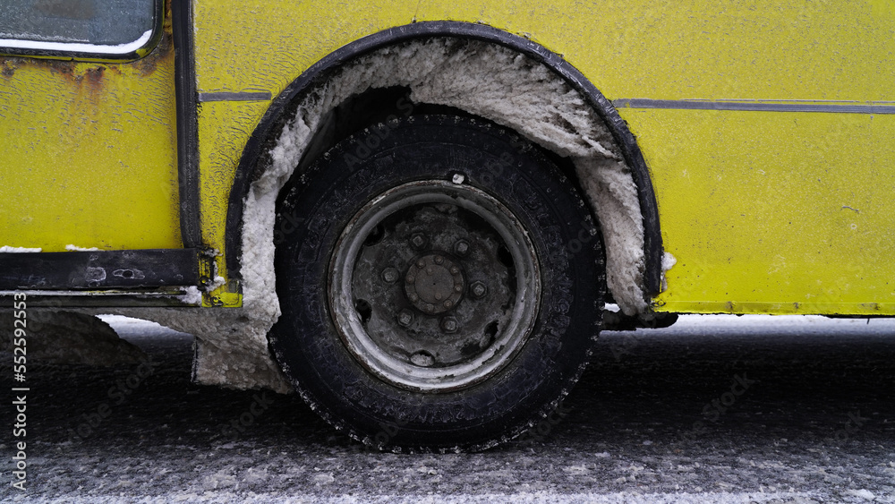 The wheel of a shuttle bus is covered with snow in the winter on the ...