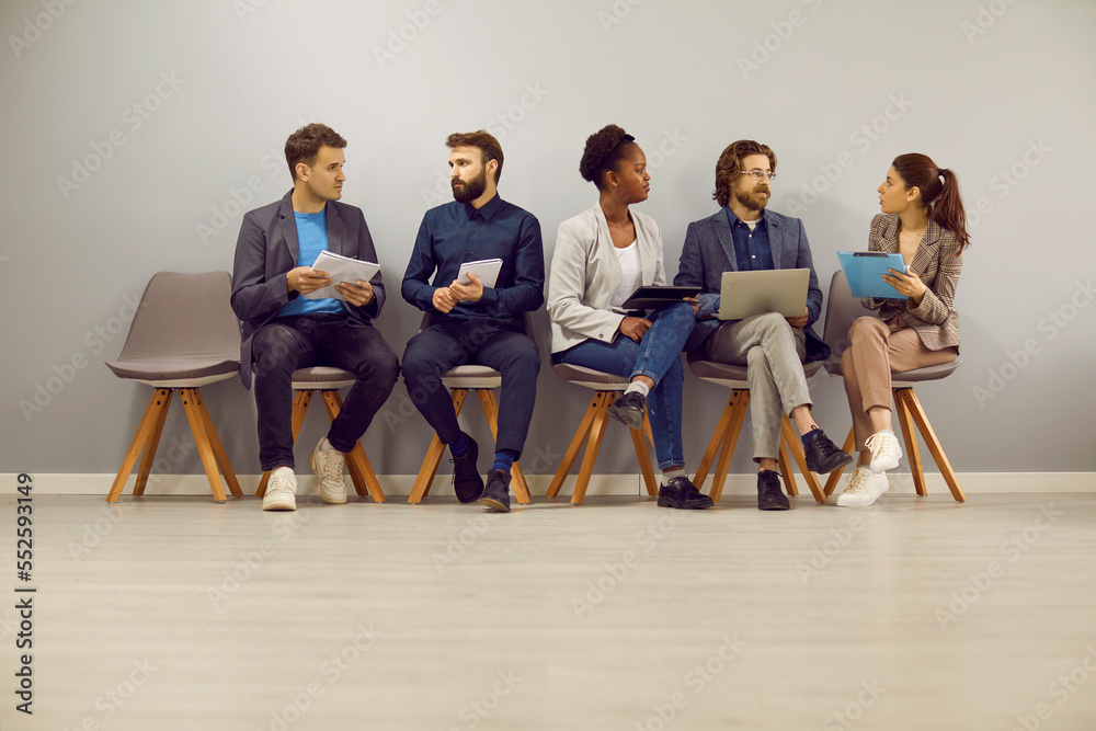 Diverse job seekers talking to each other while waiting for job ...