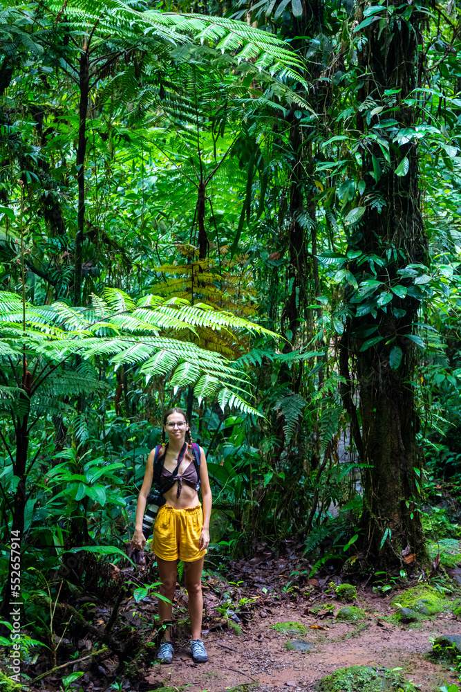 girl photographer stands under a large tree fern in the monteverde ...