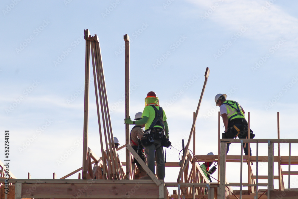 Crew of wood framing workers on top of structure of apartment building ...