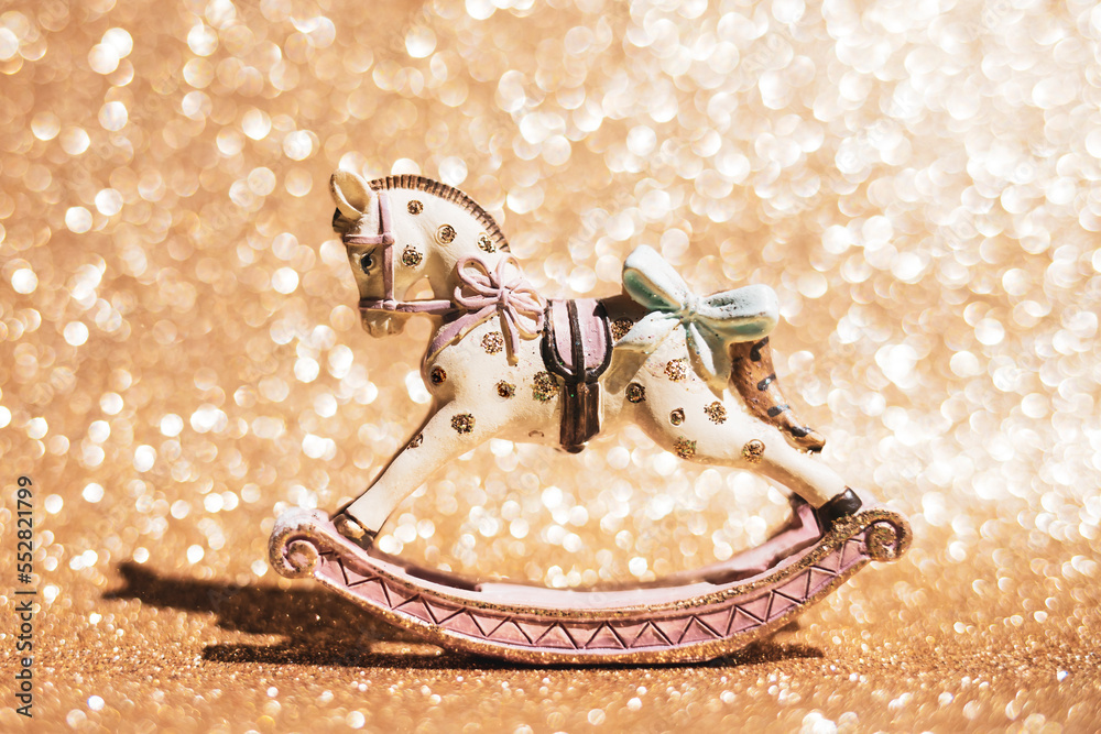 Vintage rocking horse figurine standing on a sparkling gold background ...