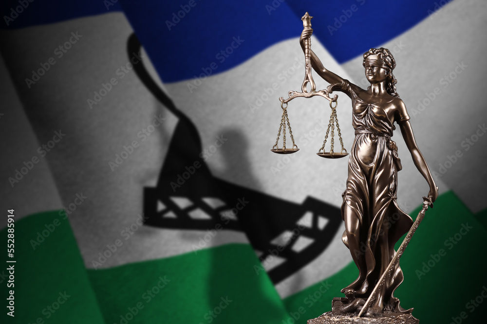 Lesotho flag with statue of lady justice and judicial scales in dark ...