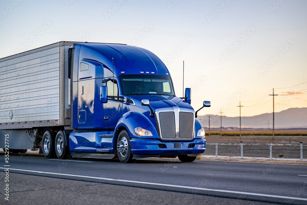 Bright blue powerful big rig semi truck transporting cargo in reefer ...