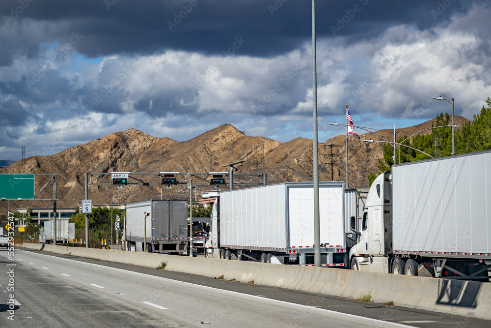 Line of big rig semi trucks with loaded semi trailers standing on the ...