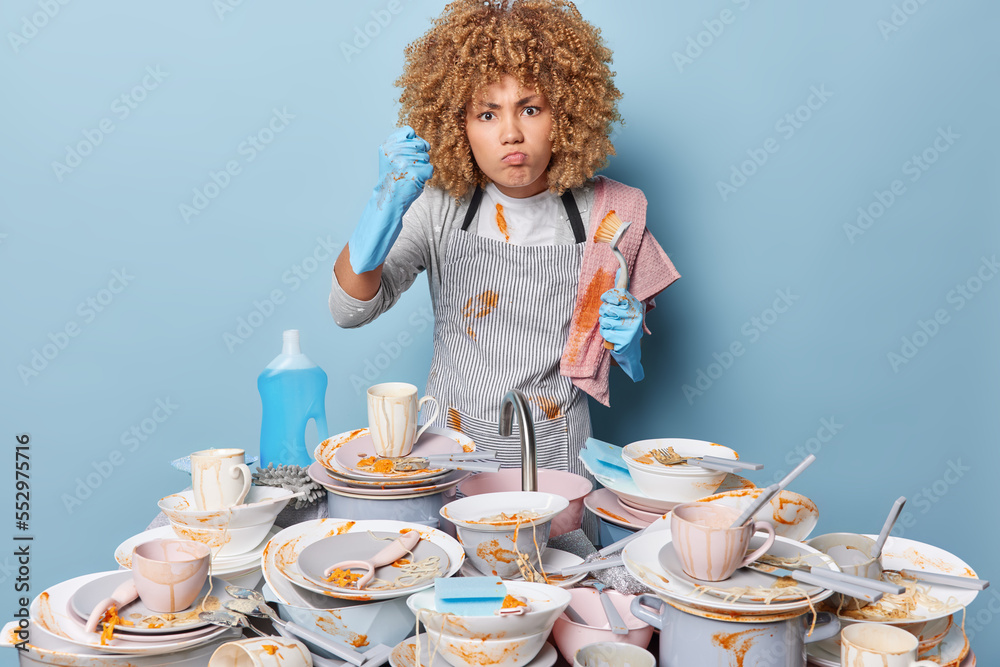 Annoyed curly housewife clenches fist and looks angrily holds brush ...