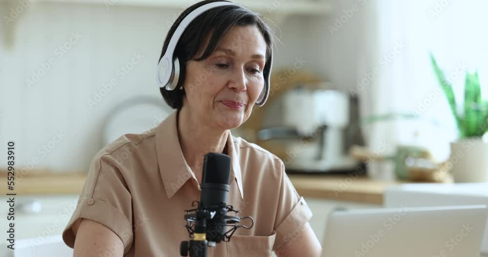 Middle-aged female vlogger talks into mike to internet audience use ...